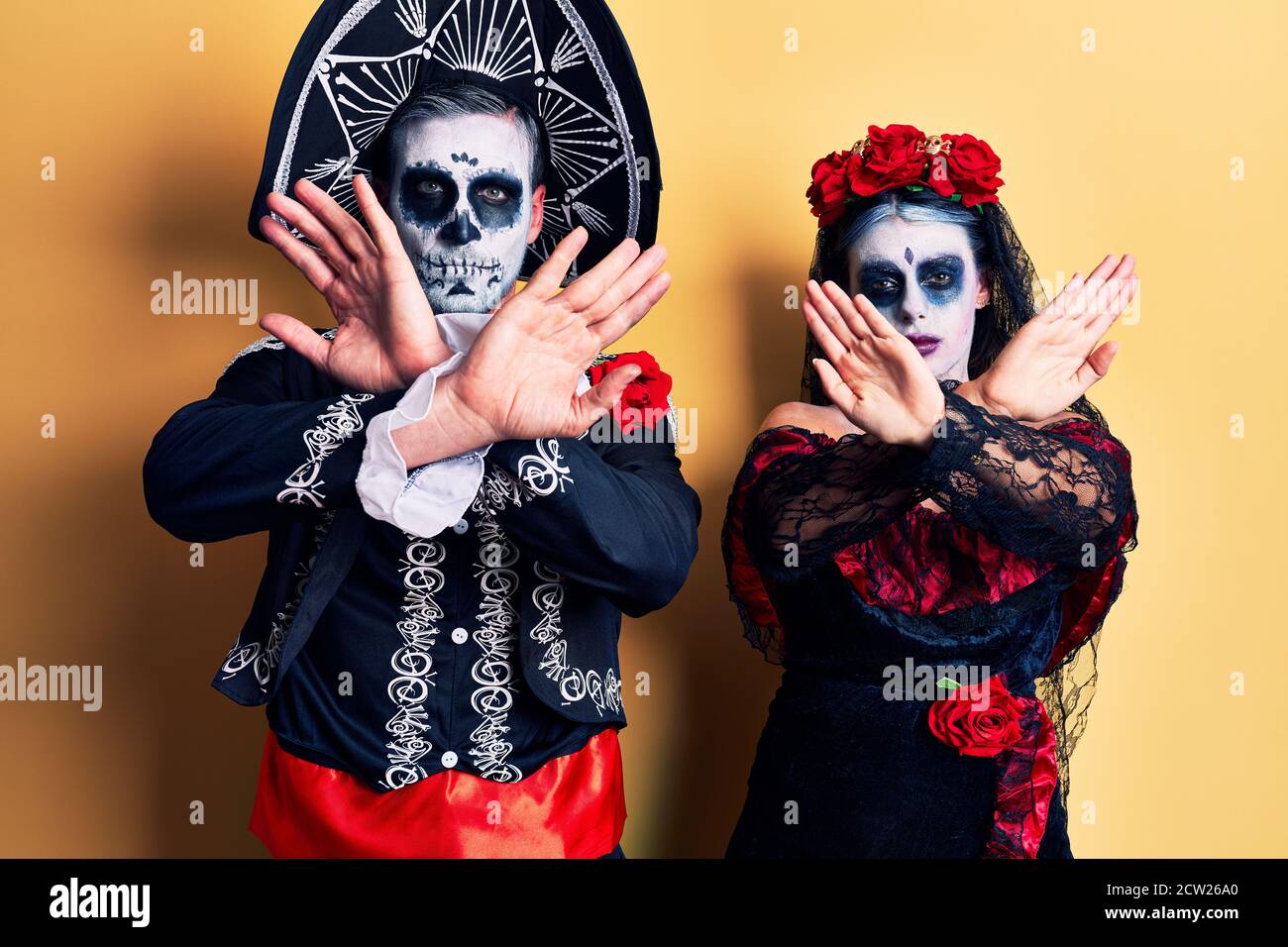 Young couple wearing mexican day of the dead costume over yellow ...