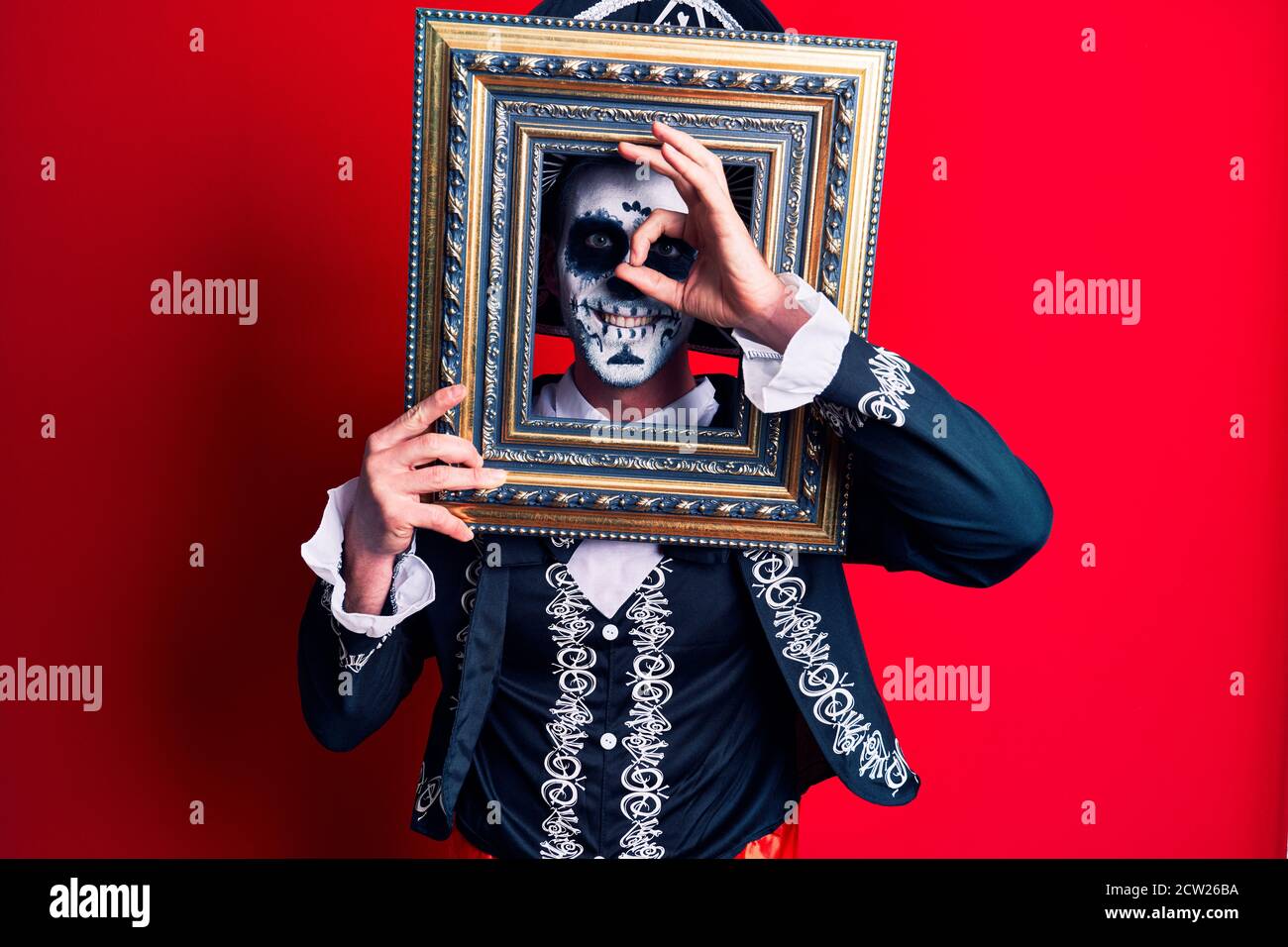 Young man wearing mexican day of the dead costume holding empty frame ...