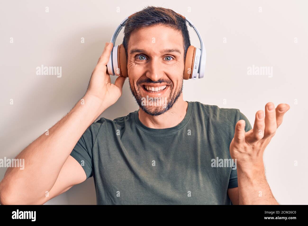 Young handsome man listening to music using headphones over isolated ...