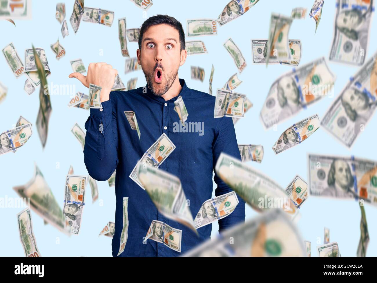 Young handsome man wearing casual shirt surprised pointing with hand ...