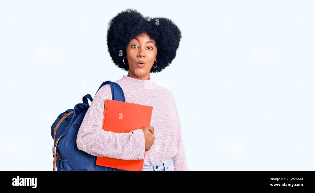 Young african american girl wearing student backpack holding book ...