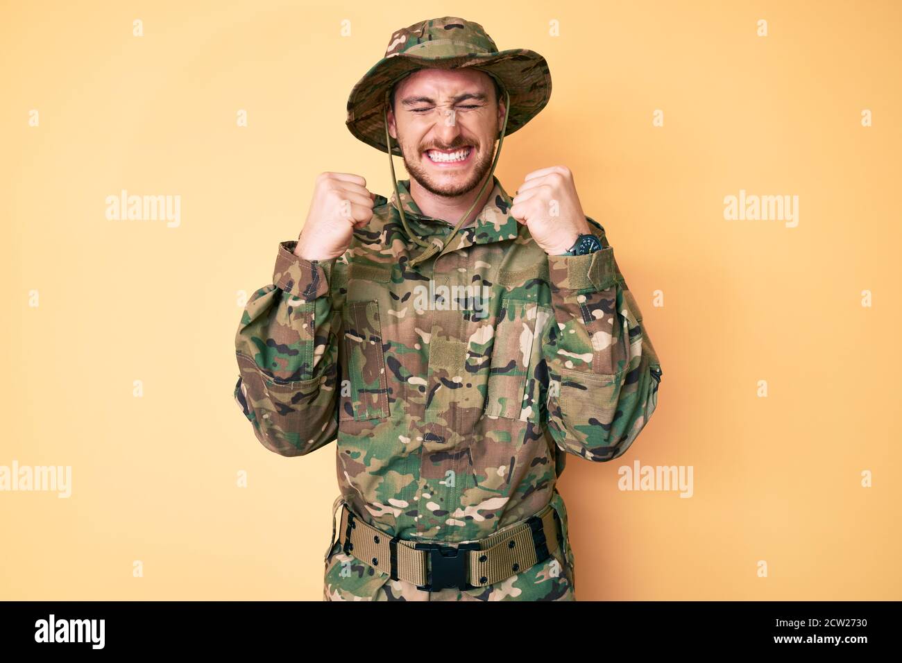 Young caucasian man wearing camouflage army uniform excited for success ...