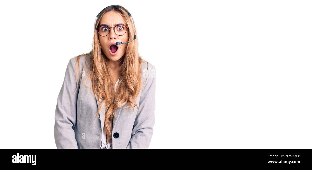 Young beautiful blonde woman wearing call center agent headset afraid ...