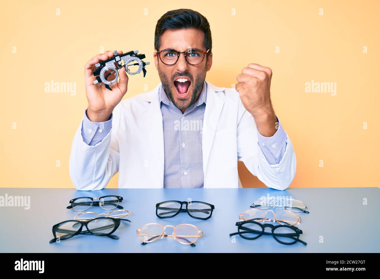 Young hispanic man holding glasses at the optic annoyed and frustrated ...