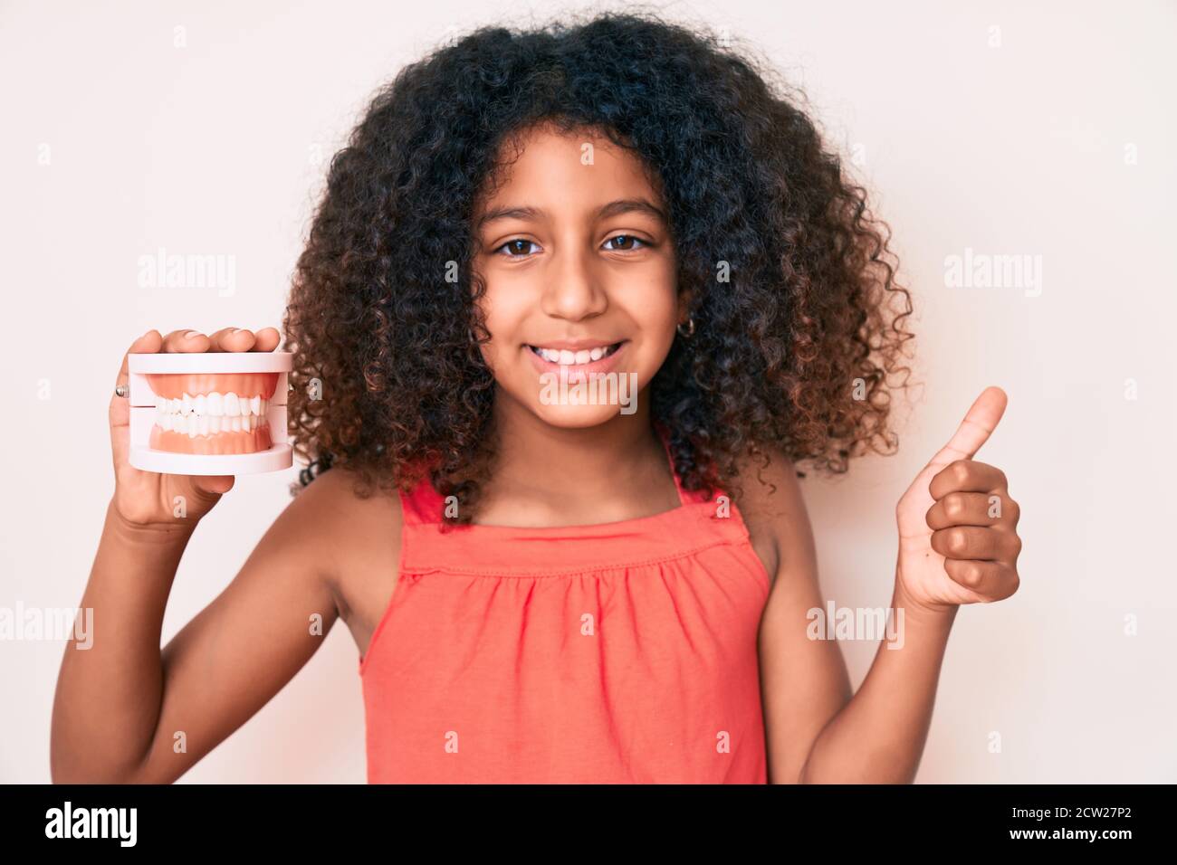 African american child with curly hair holding denture smiling happy ...