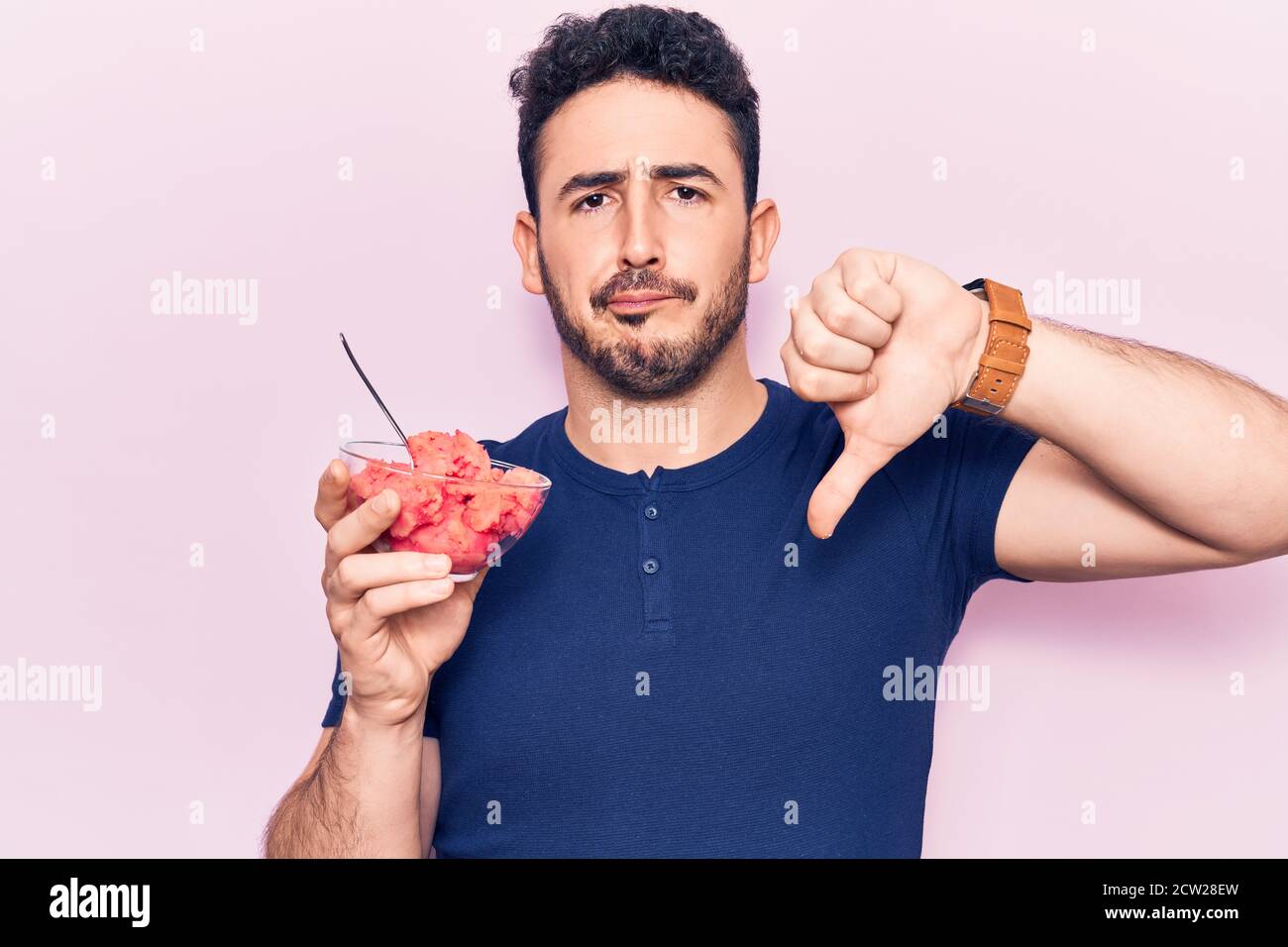 Young hispanic man holding ice cream with angry face, negative sign ...