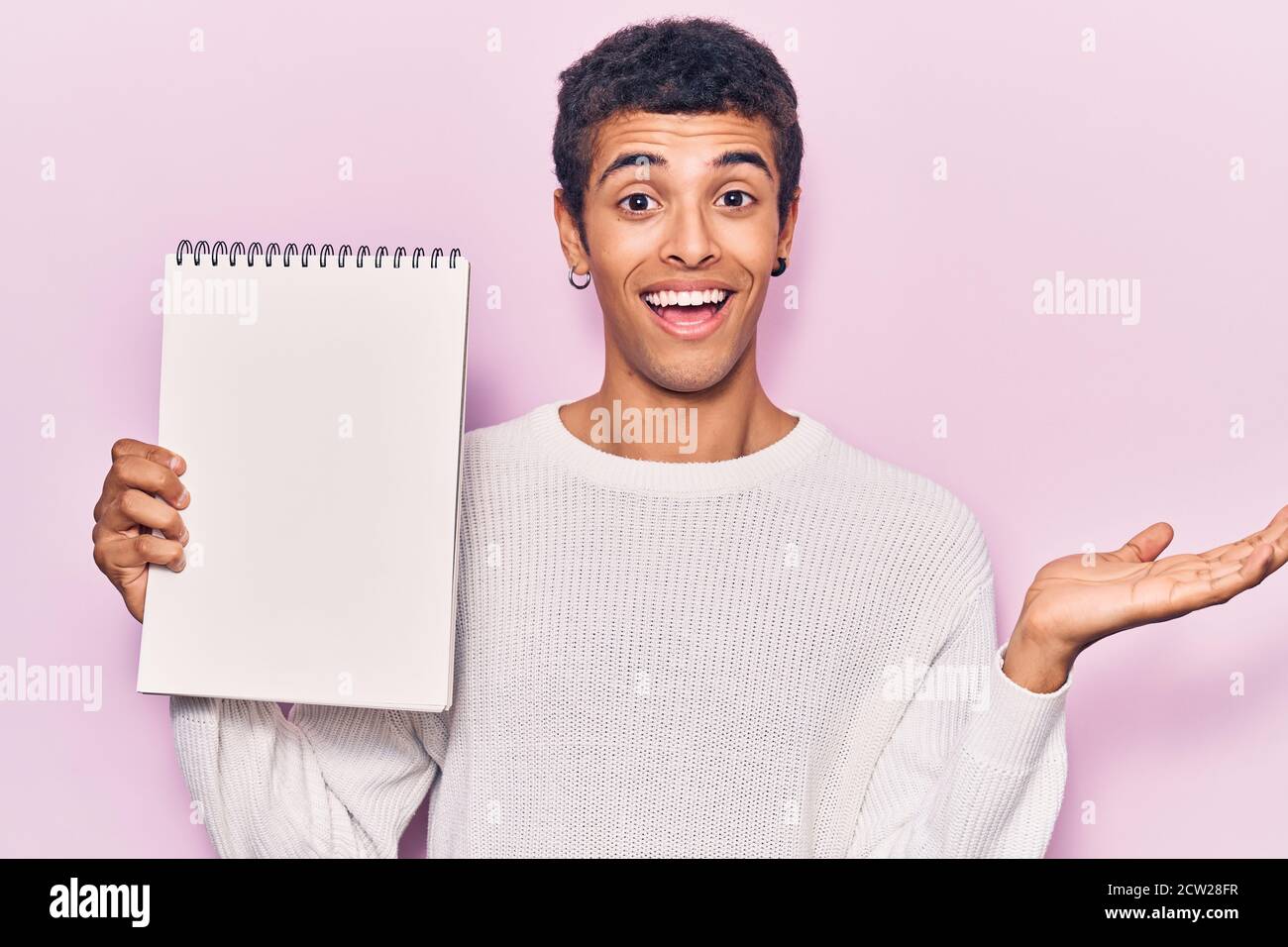 Young african amercian man holding notebook celebrating achievement ...