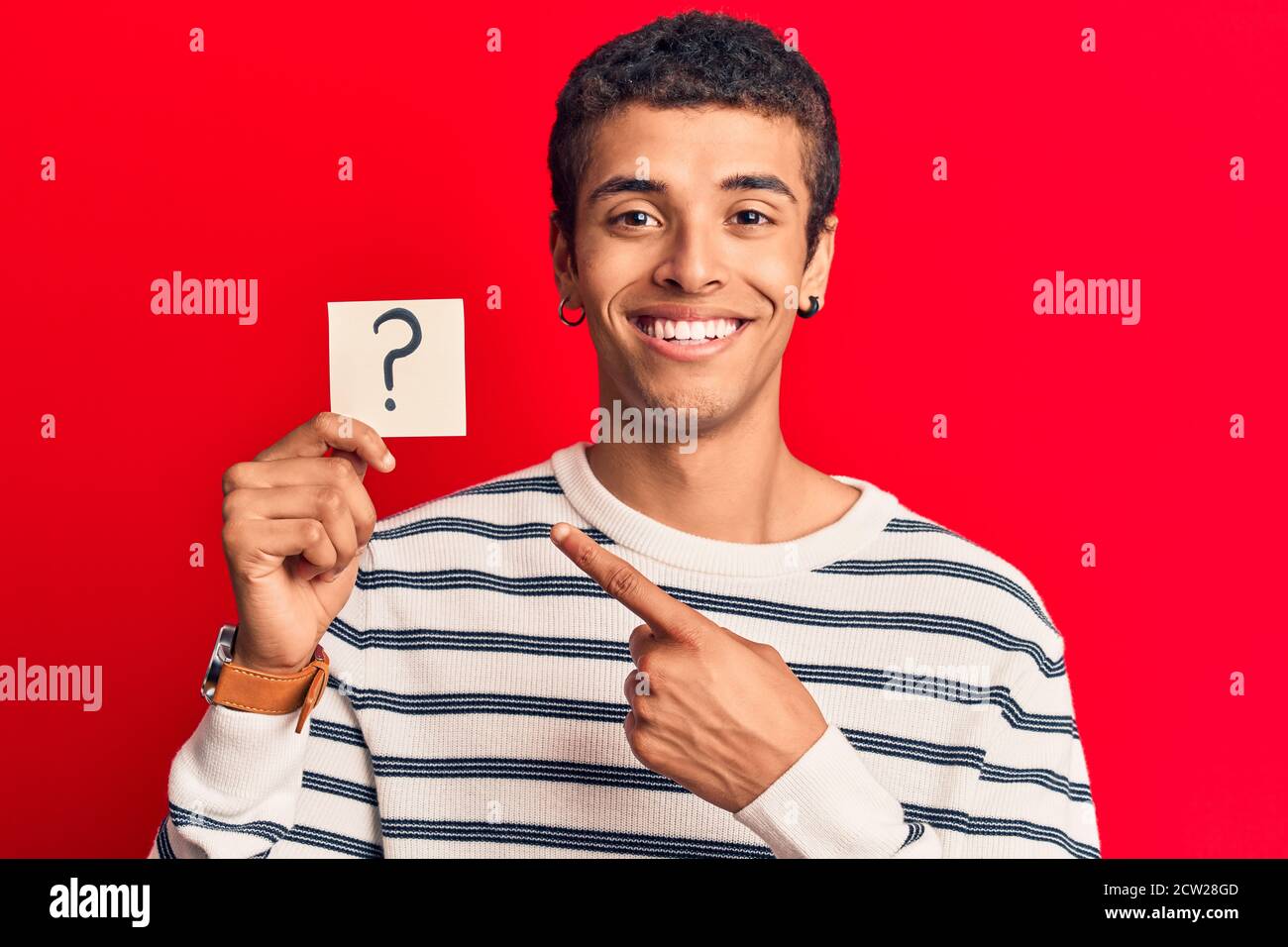 Young african amercian man holding question mark reminder smiling happy ...