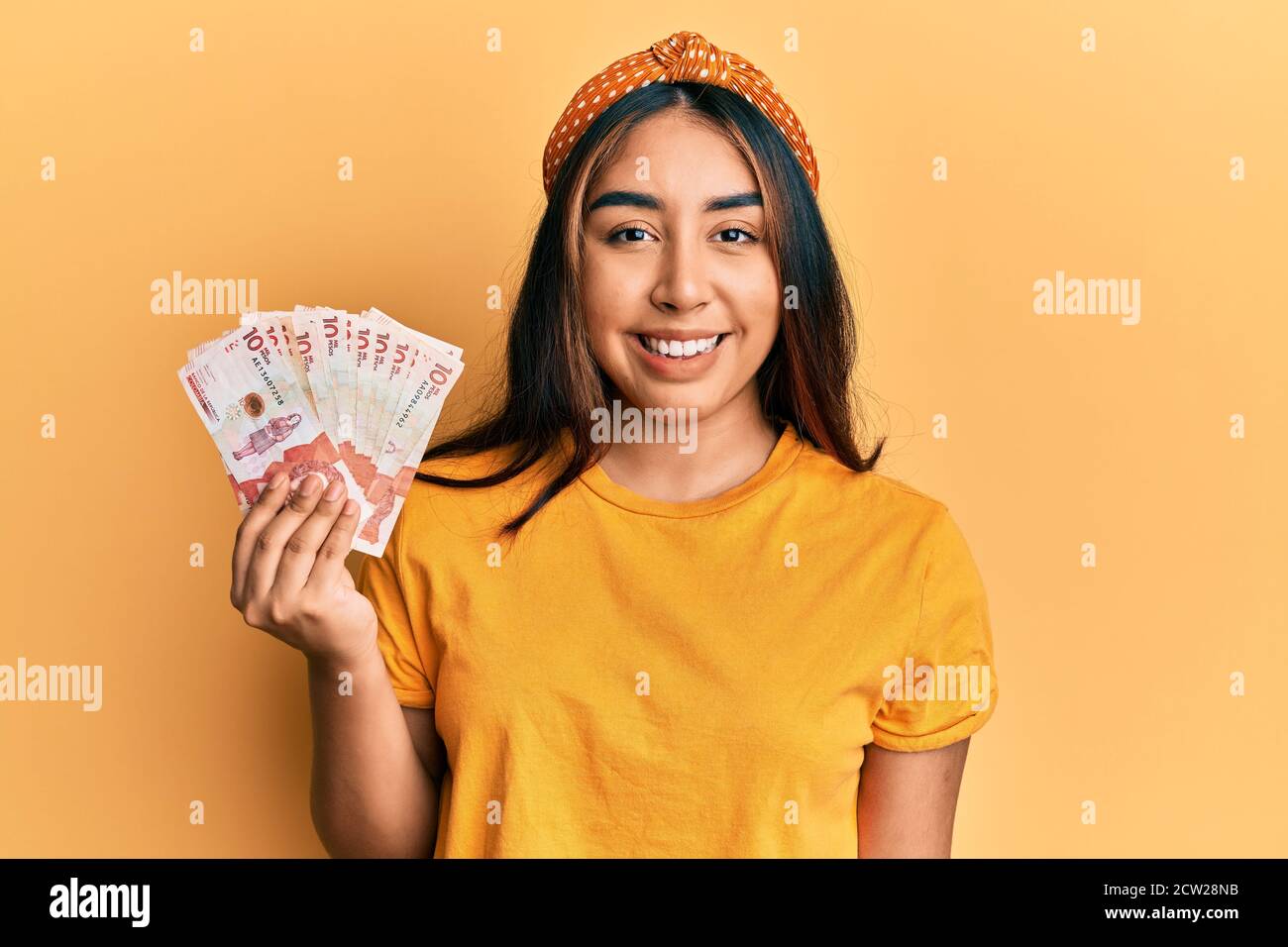 Young latin woman holding colombian pesos looking positive and happy ...