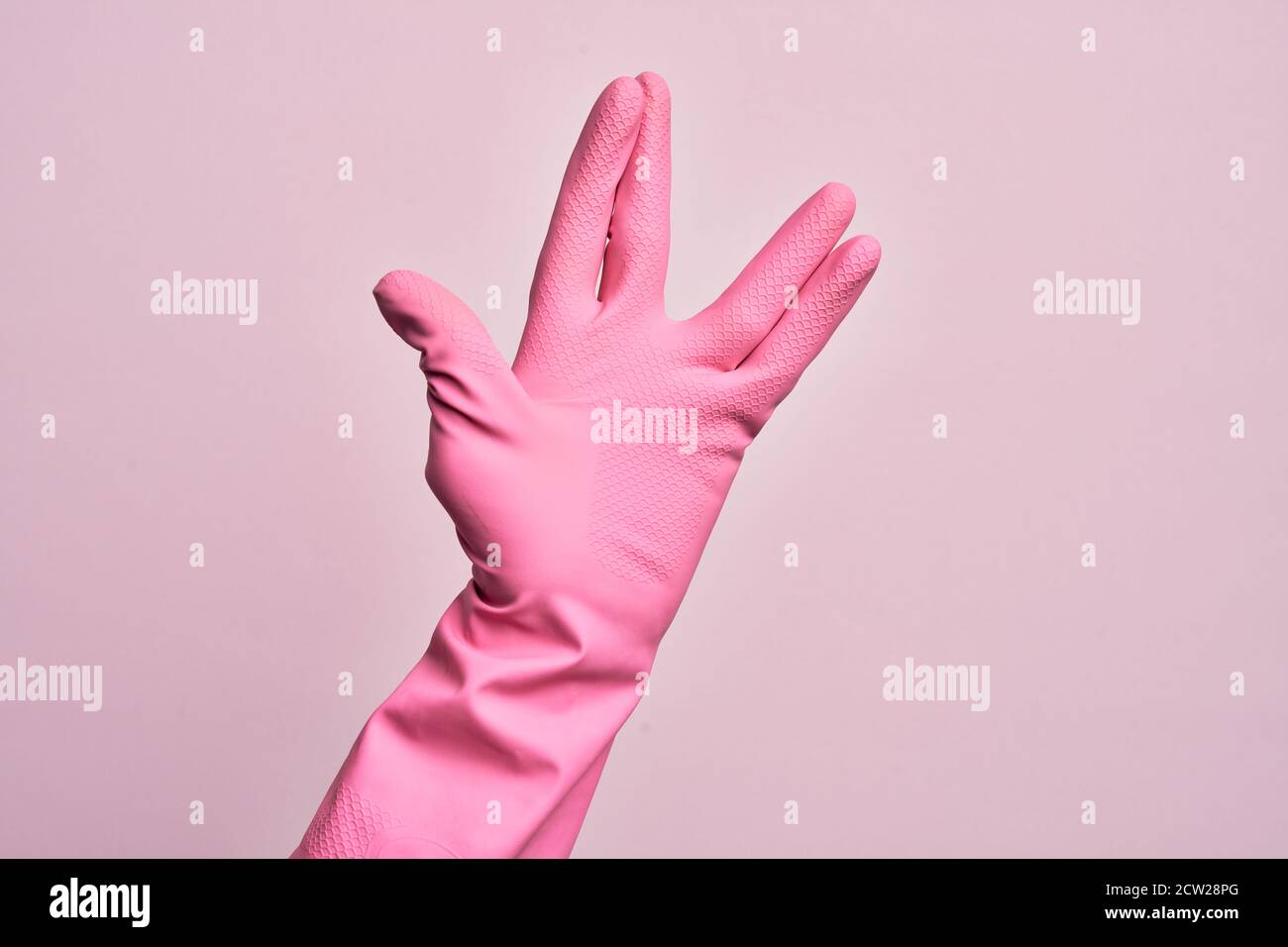 Hand of caucasian young man with cleaning glove over isolated pink ...