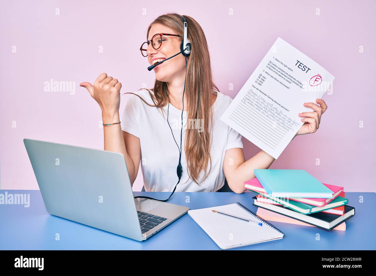 Young blonde girl showing failed exam sitting on the table pointing ...