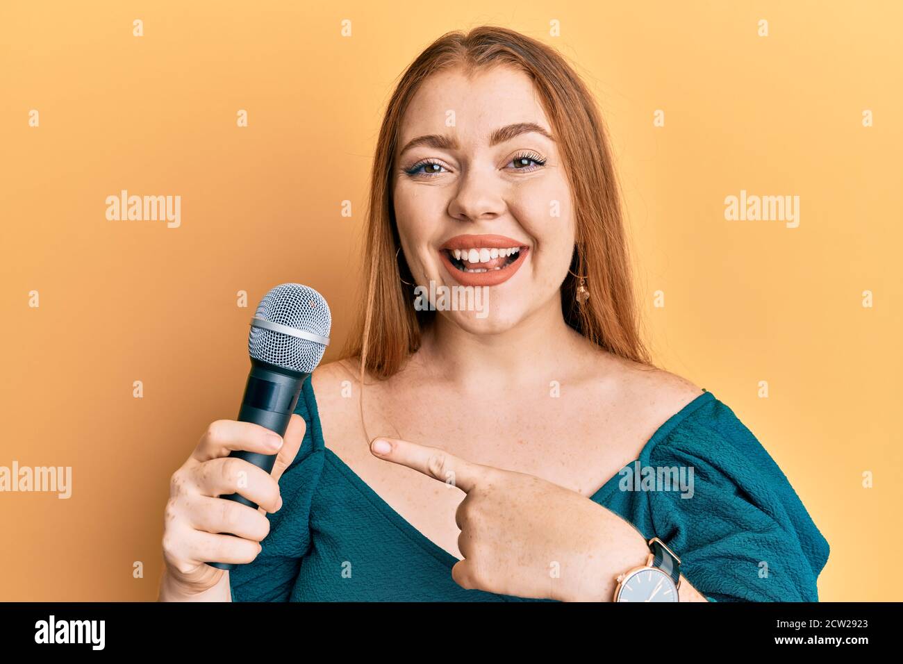 Young beautiful redhead woman singing song using microphone smiling ...