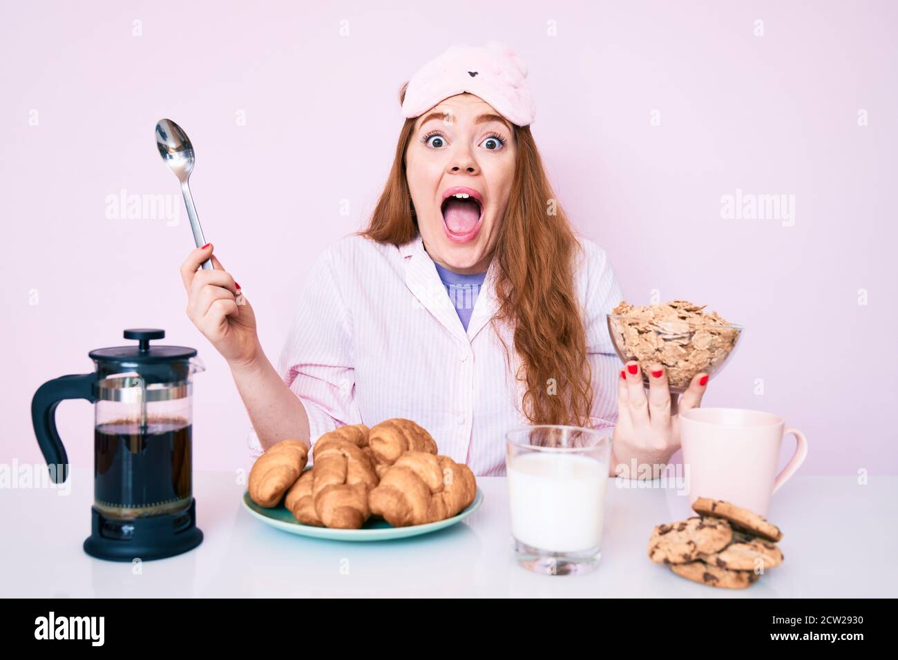 Young beautiful redhead woman sitting on the table having breakfast ...