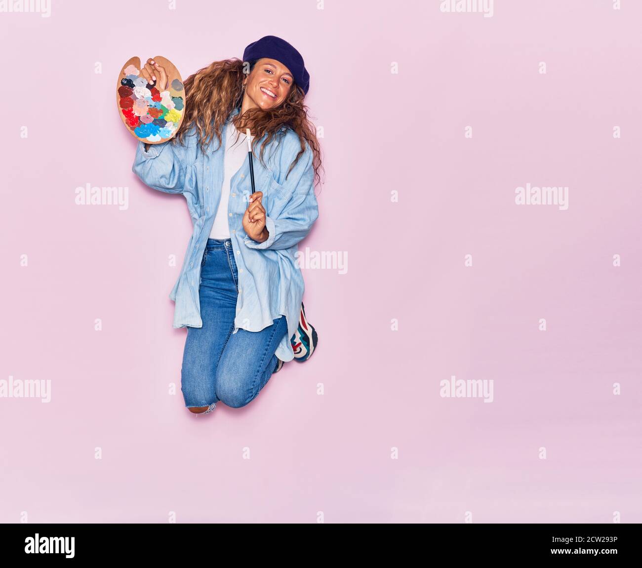 Young beautiful curly artist woman with tattoo wearing french beret ...