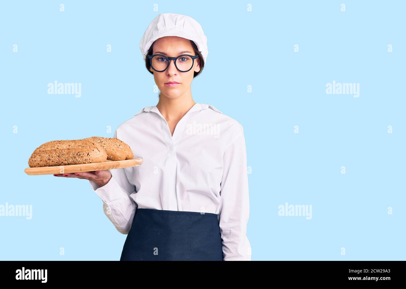 Beautiful brunette young woman wearing baker uniform holding homemade ...