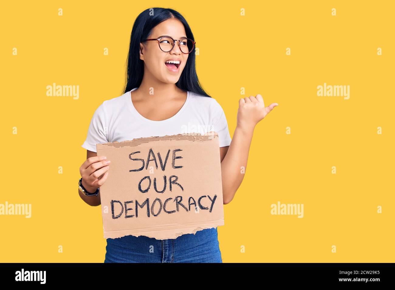 Young beautiful asian girl holding save our democracy protest banner ...