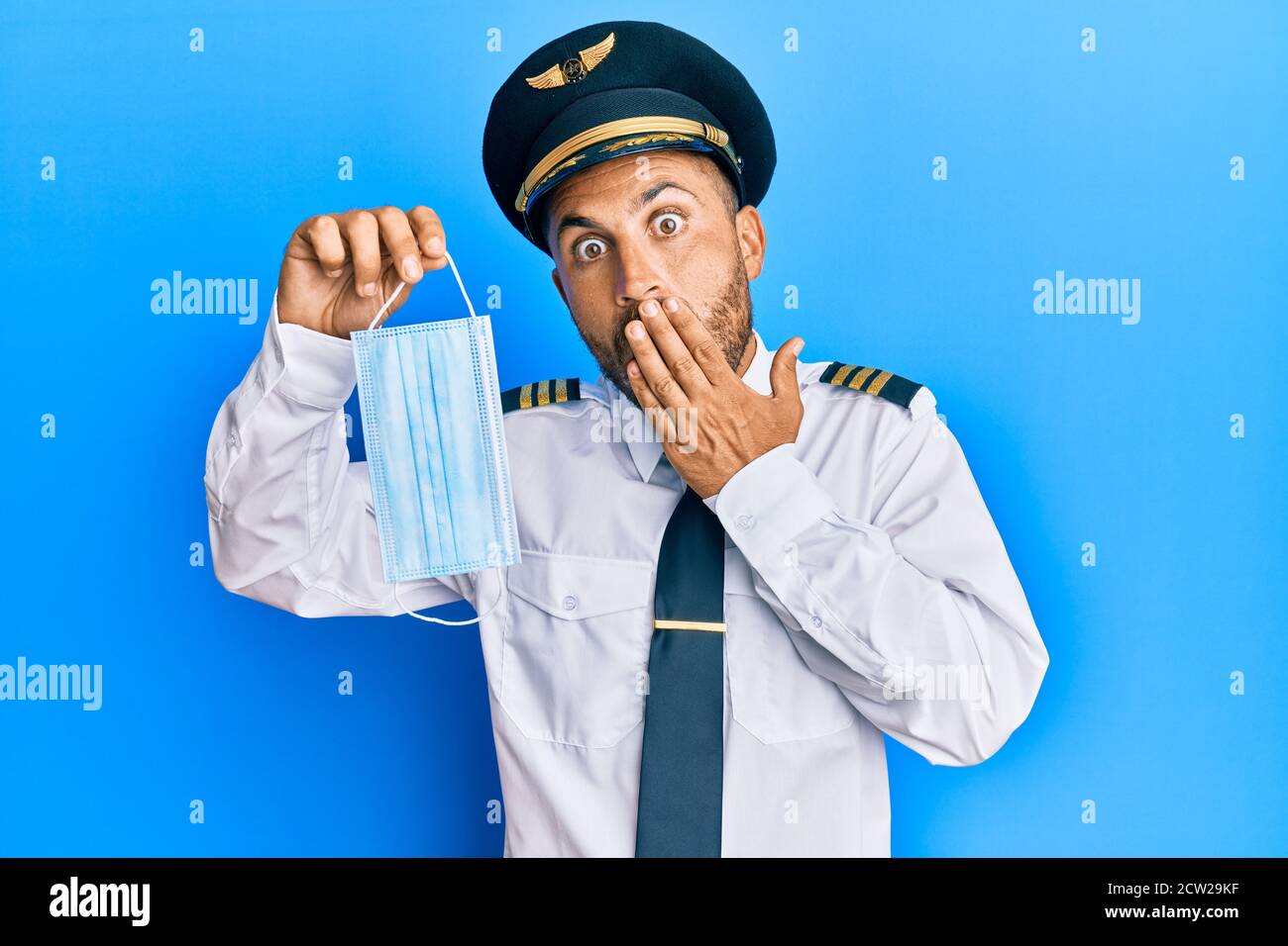 Handsome man with beard wearing airplane pilot uniform holding safety ...