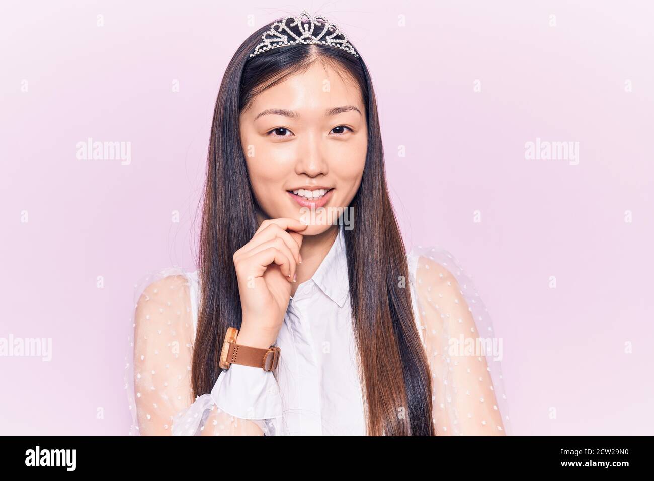 Young beautiful chinese woman wearing princess crown smiling looking ...