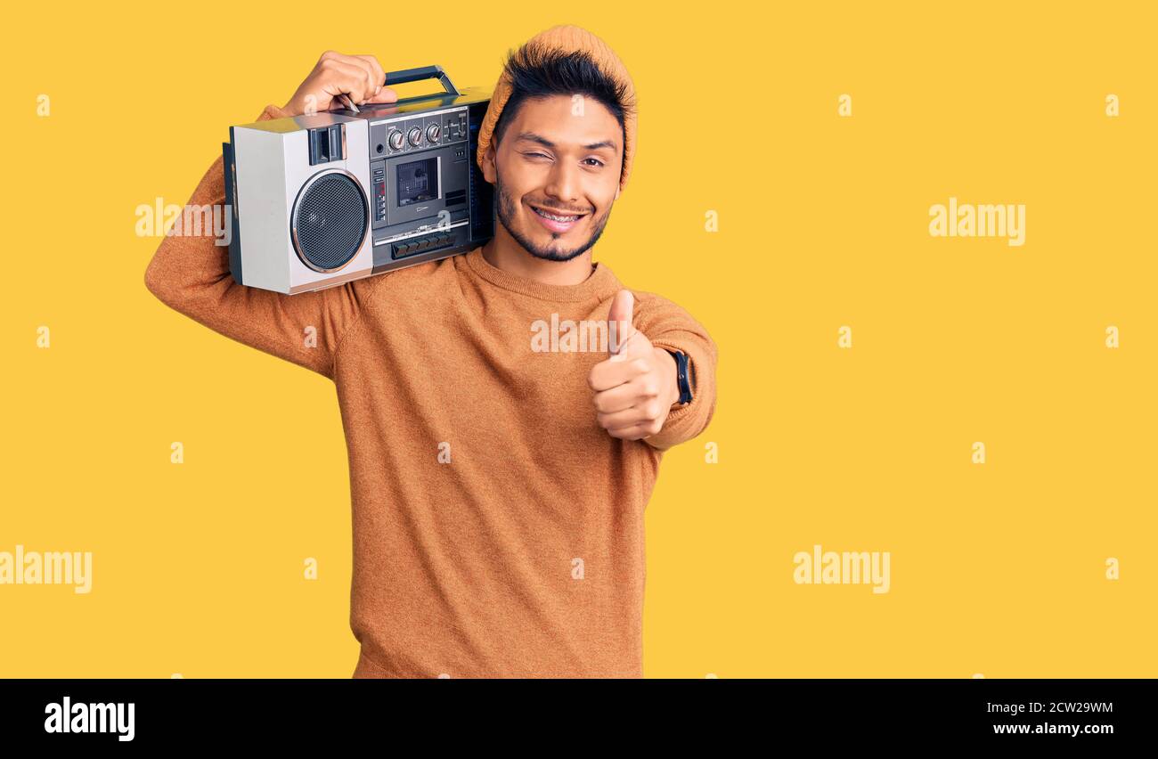 Handsome latin american young man holding boombox, listening to music ...