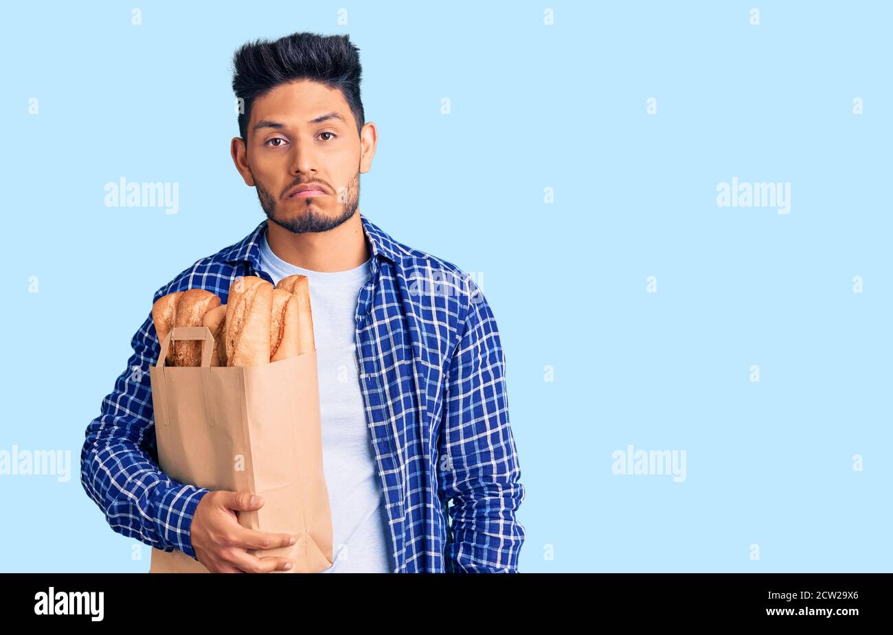 Handsome latin american young man holding paper bag with bread ...