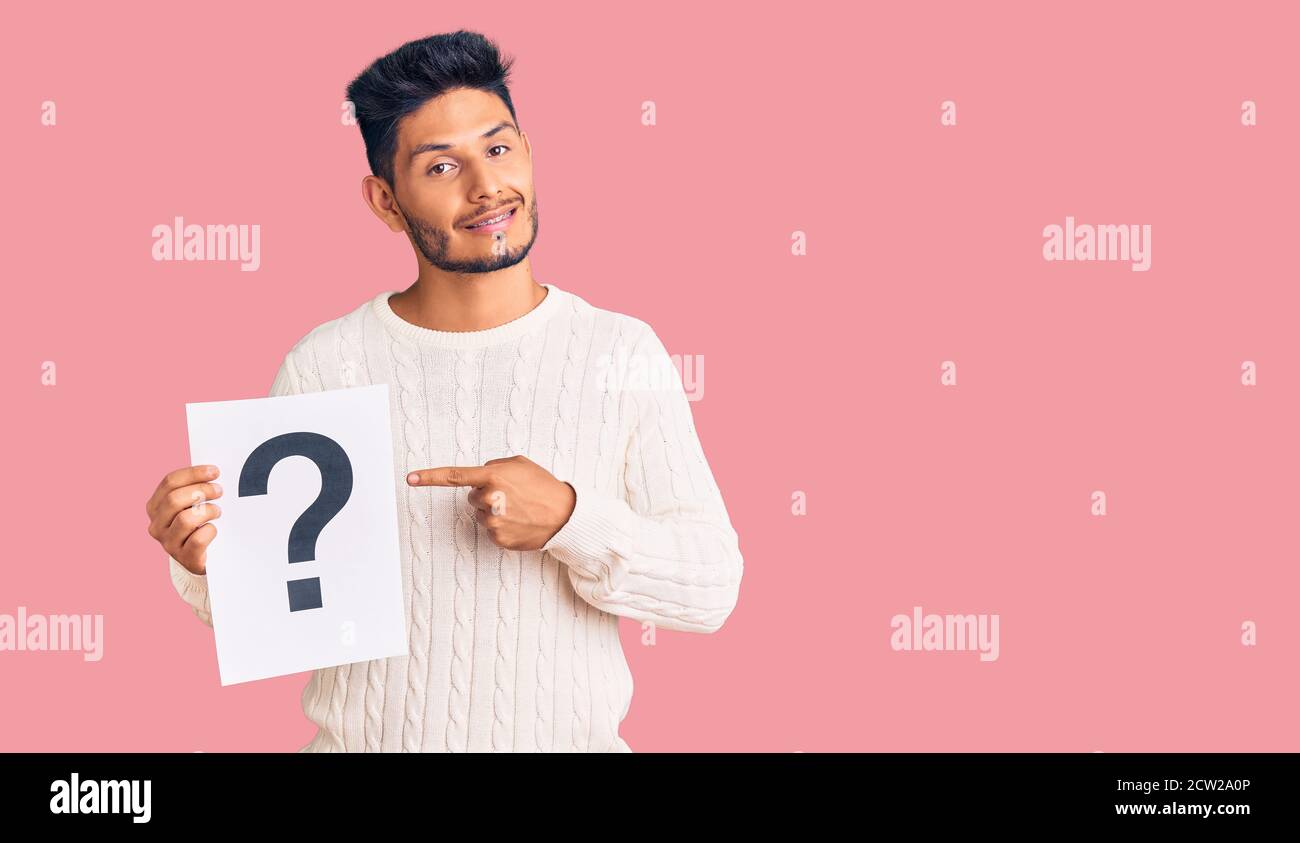Handsome latin american young man holding question mark smiling happy ...