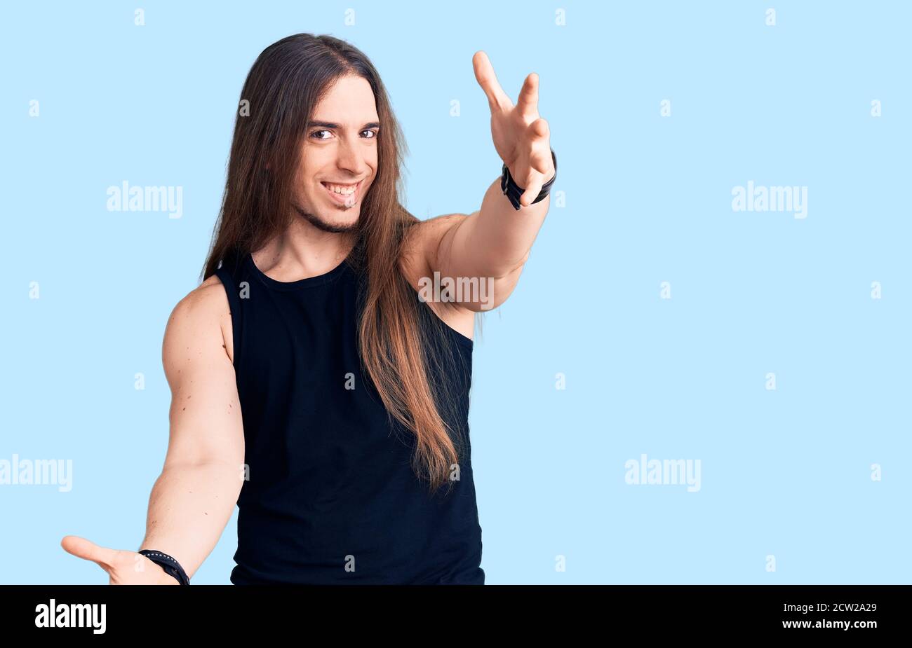 Young adult man with long hair wearing goth style with black clothes ...