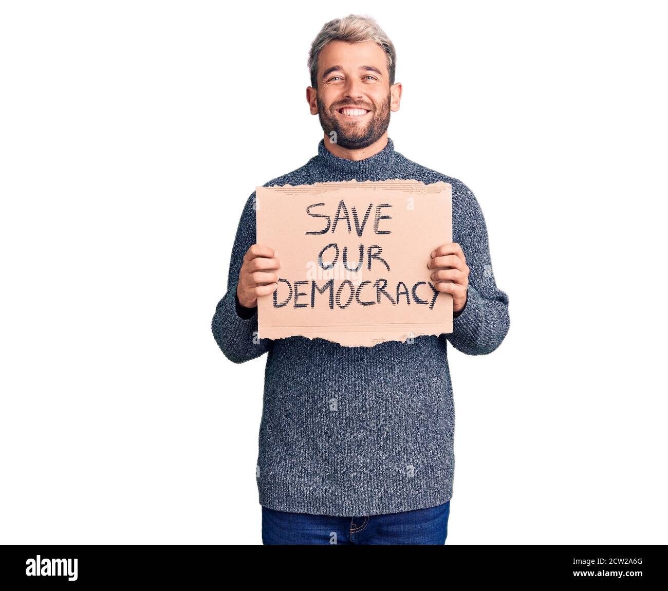 Young blond man holding save our democracy cardboard banner looking ...