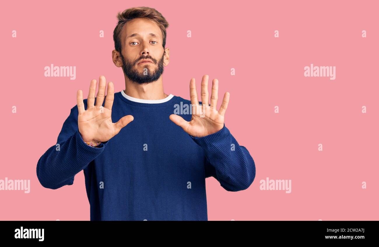 Handsome blond man with beard wearing casual sweater moving away hands ...