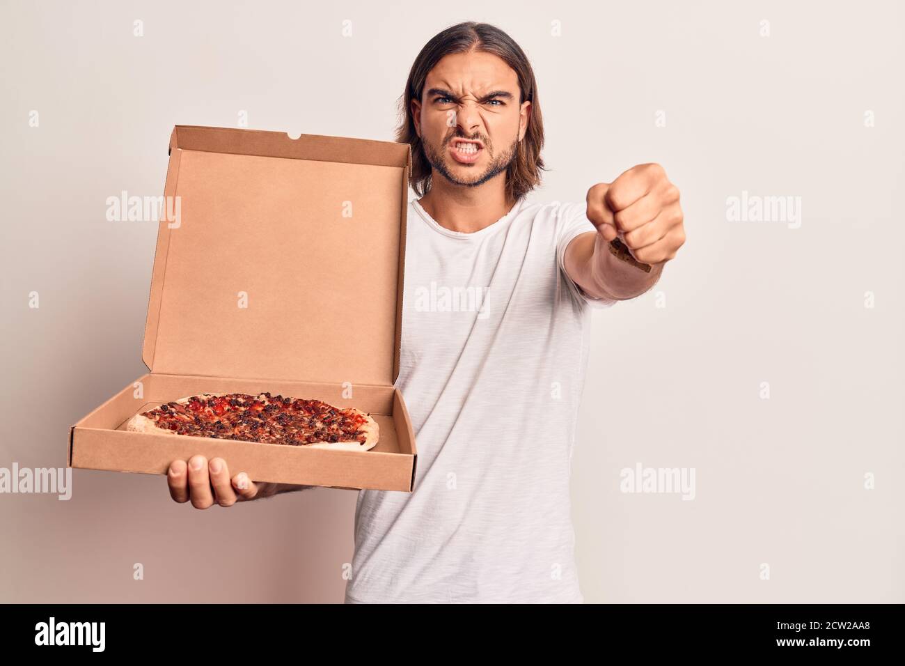 Young handsome man holding delivery pizza box annoyed and frustrated ...