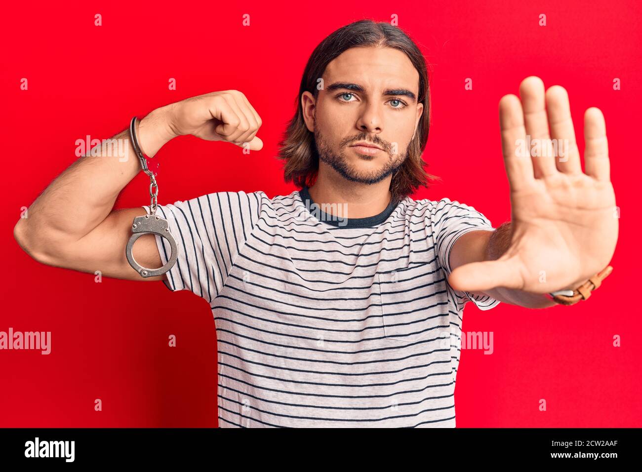 Young handsome man wearing prisoner handcuffs with open hand doing stop ...