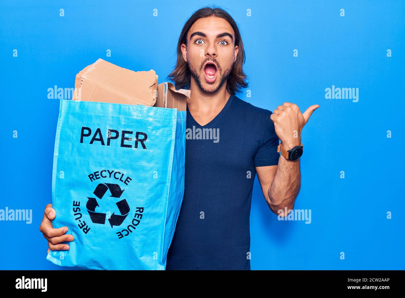 Young handsome man holding recycling wastebasket with paper and ...