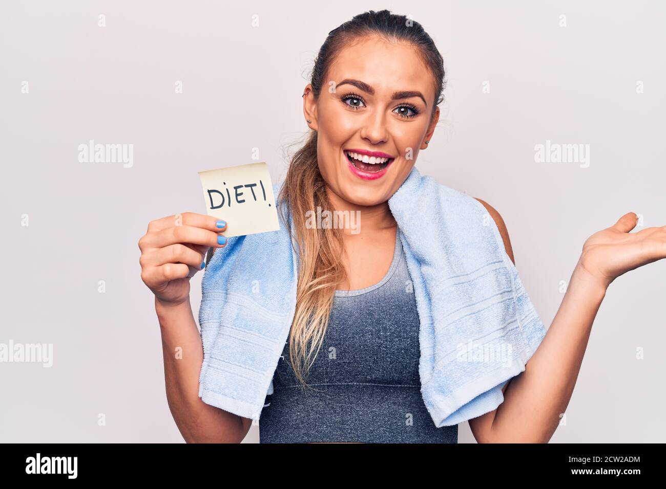 Young beautiful blonde sporty woman using towel holding diet reminder ...