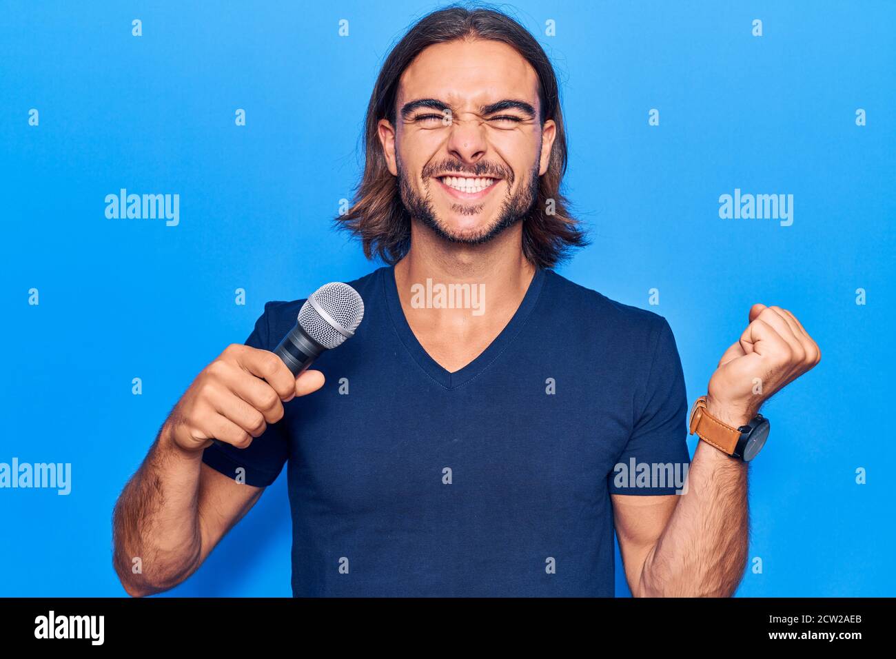Young handsome man singing song using microphone screaming proud ...