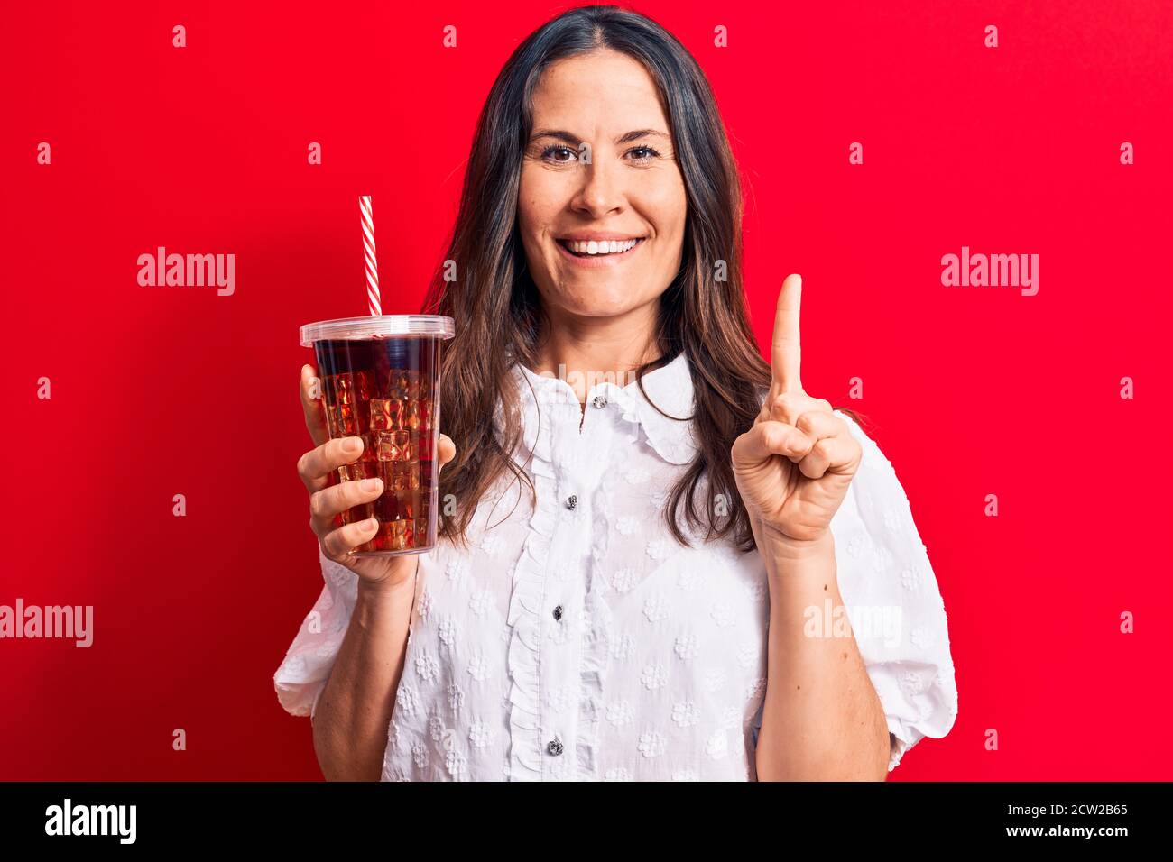 Beautiful brunette woman drinking cola refreshment beverage using straw ...