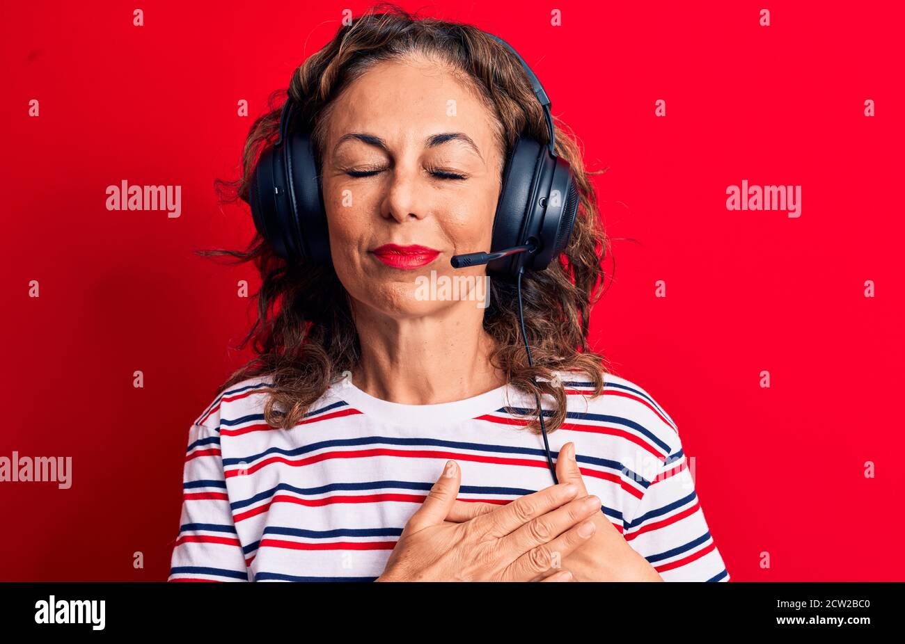 Middle age brunette gamer woman playing video game using headphones and ...