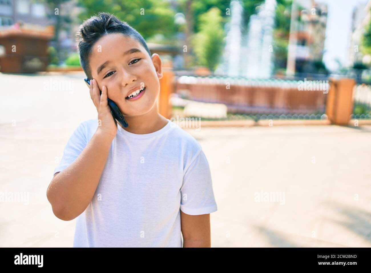 Adorable boy smiling happy talking on the smartphone at street of city ...