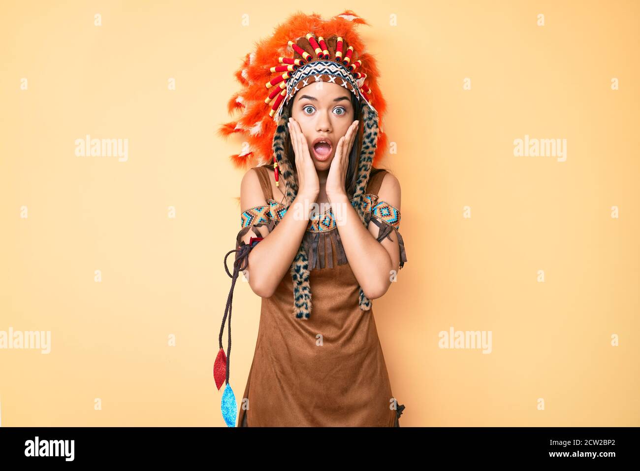 Young beautiful latin girl wearing indian costume afraid and shocked ...