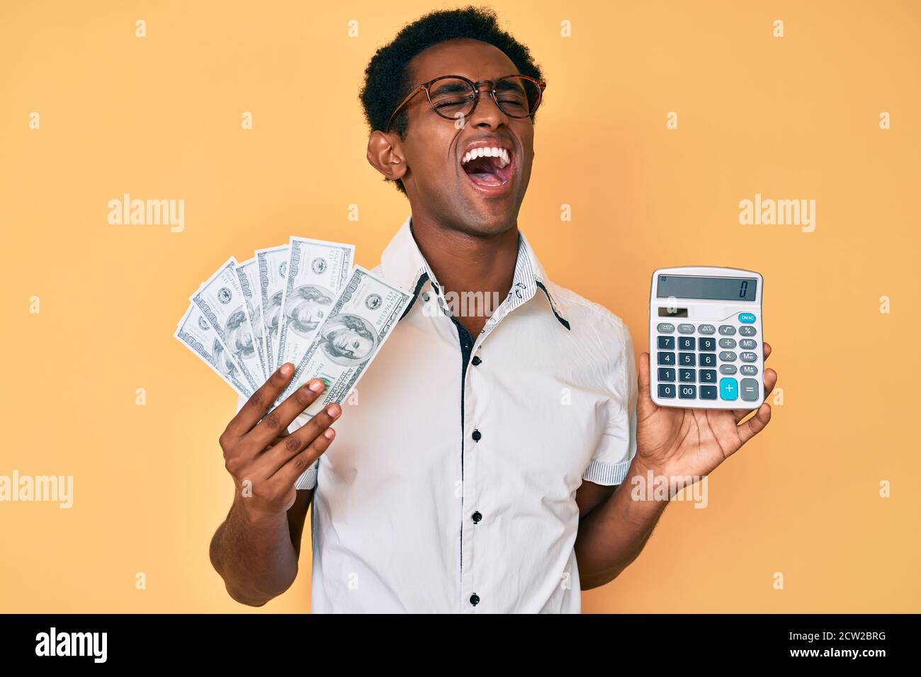 African handsome man holding dollars calculating savings angry and mad ...