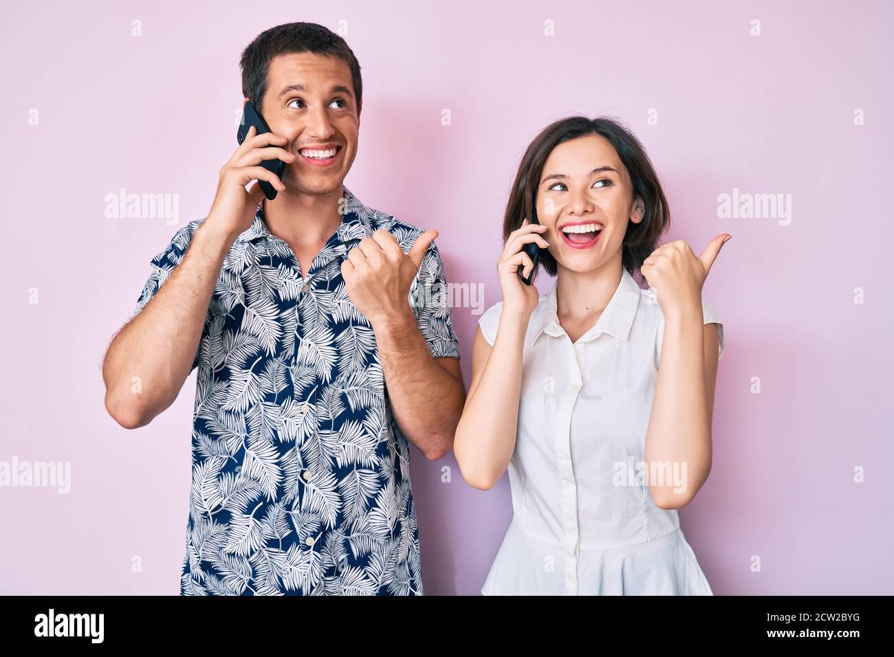 Beautiful couple having conversation talking on the smartphone pointing ...