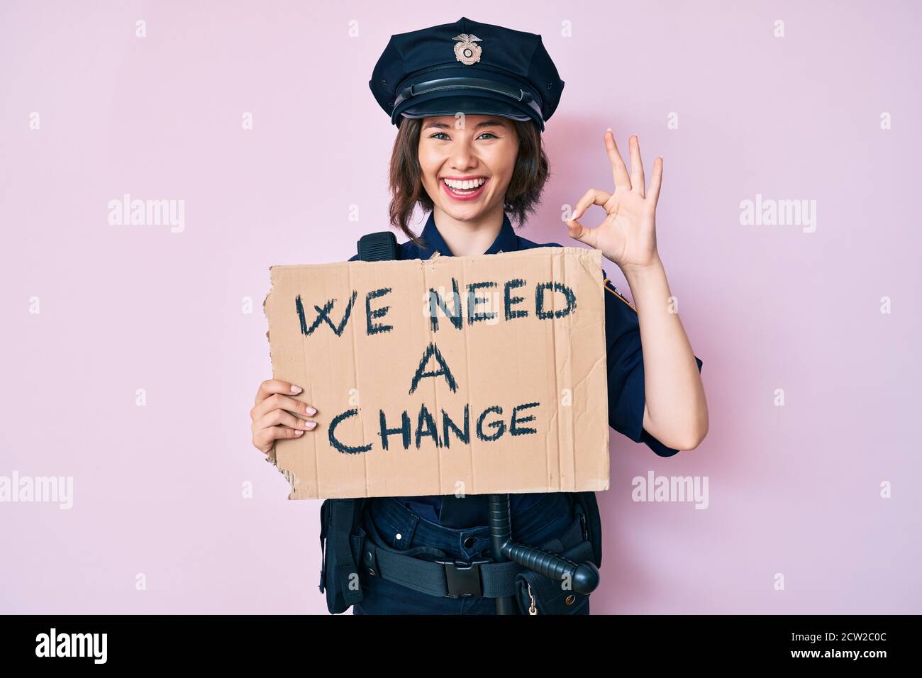 Young beautiful woman wearing police uniform holding we need a change ...