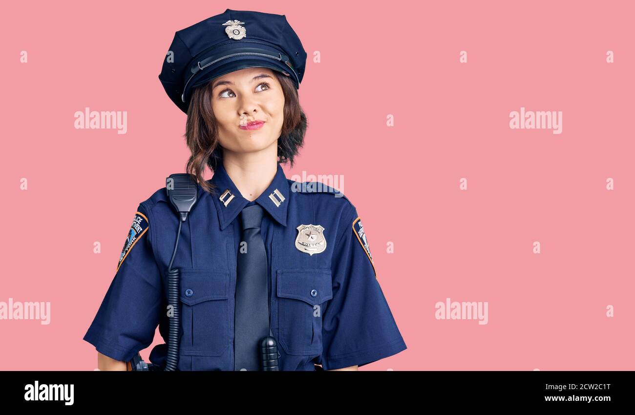 Young beautiful girl wearing police uniform smiling looking to the side ...