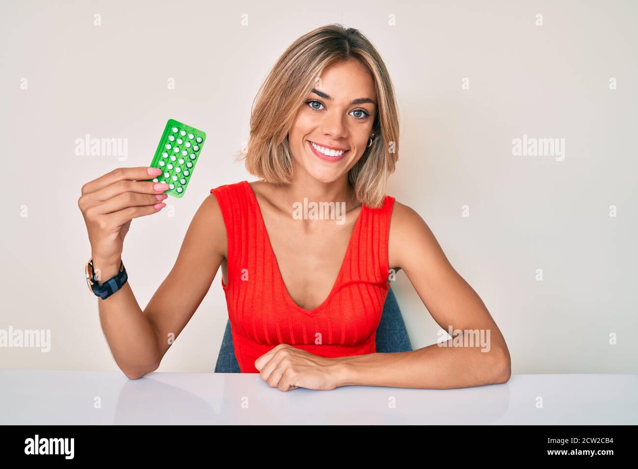 Beautiful caucasian woman holding birth control pills looking positive ...