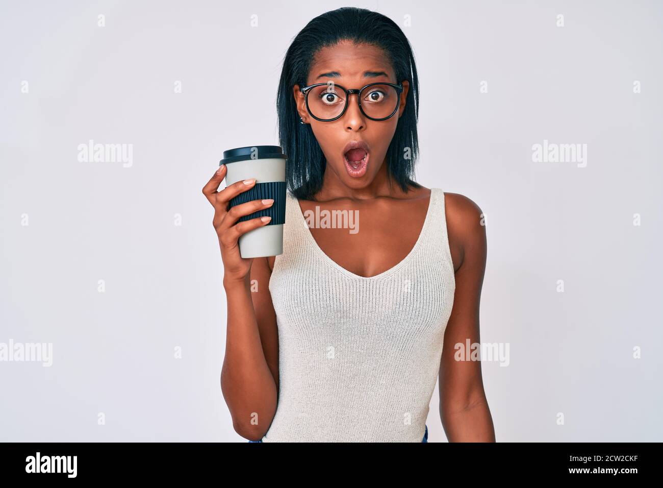 Young african american woman holding take away coffee scared and amazed ...