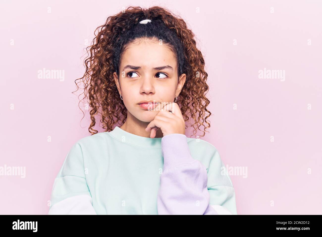 Beautiful kid girl with curly hair wearing casual clothes serious face ...