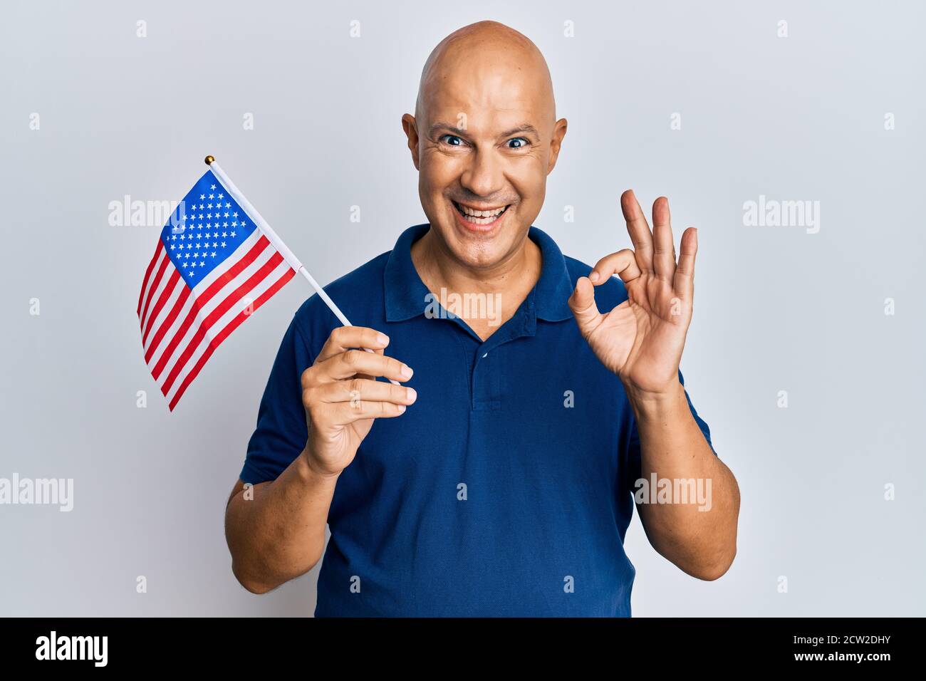 Middle age bald man holding united states flag doing ok sign with ...