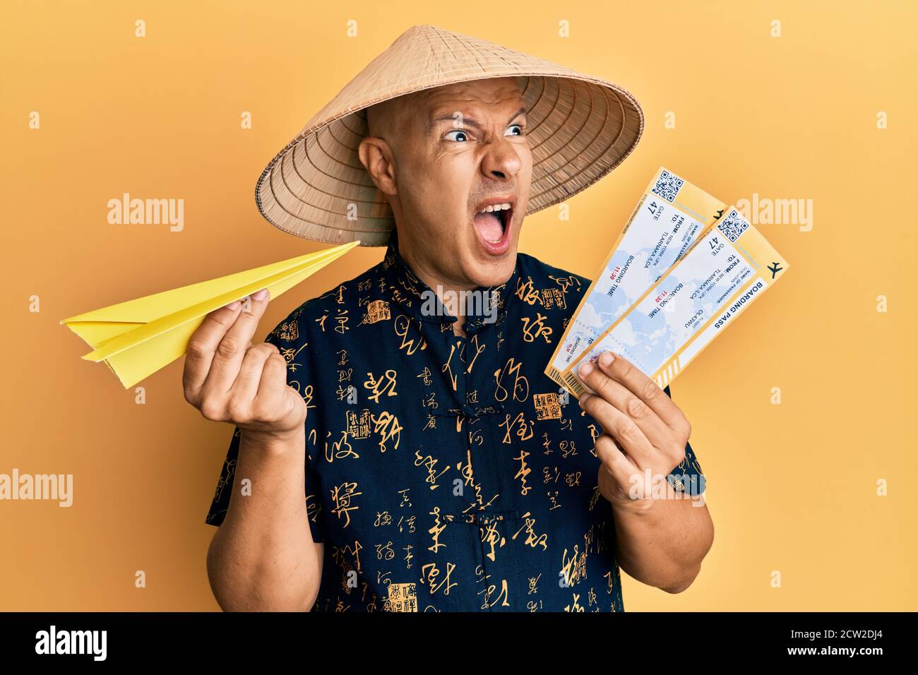 Middle age bald man wearing traditional asian hat holding boarding pass ...