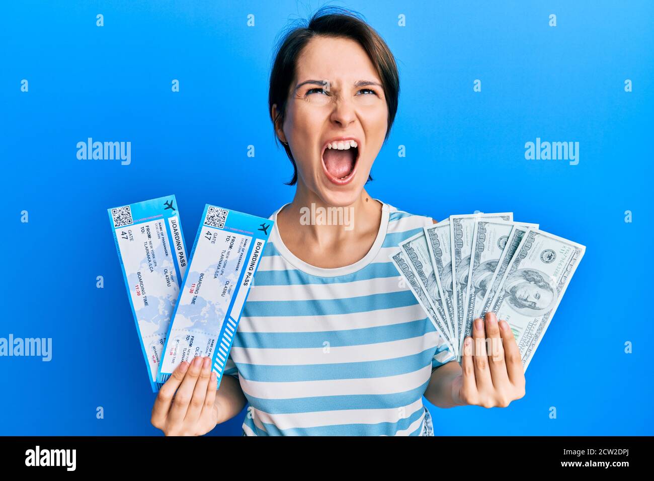 Young brunette woman with short hair holding boarding pass and dollars ...