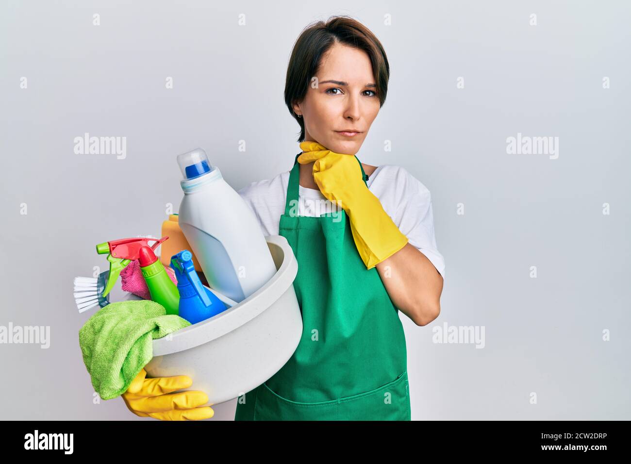 Young brunette woman with short hair wearing apron holding cleaning ...