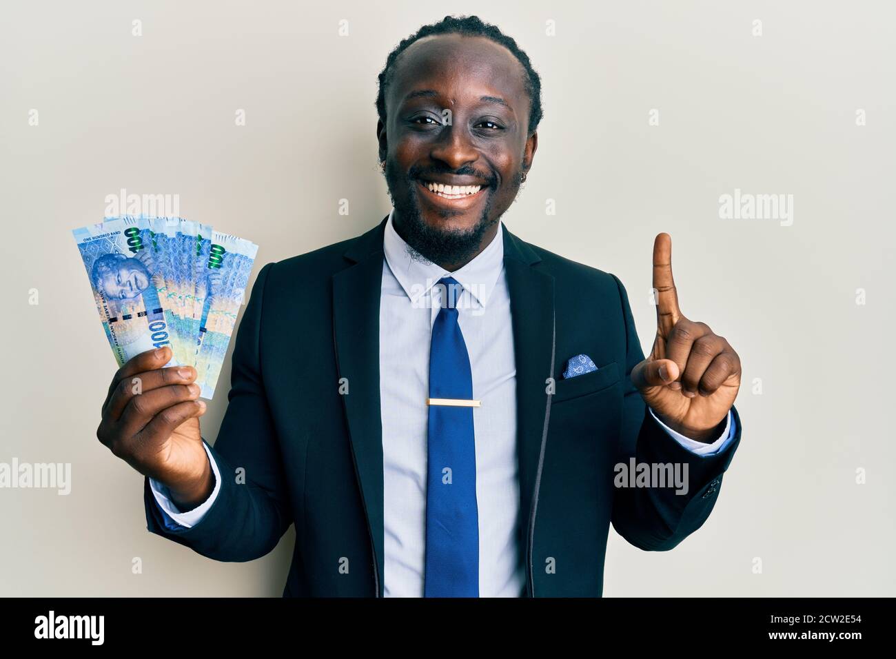 Handsome young black man wearing business suit holding 100 rands ...