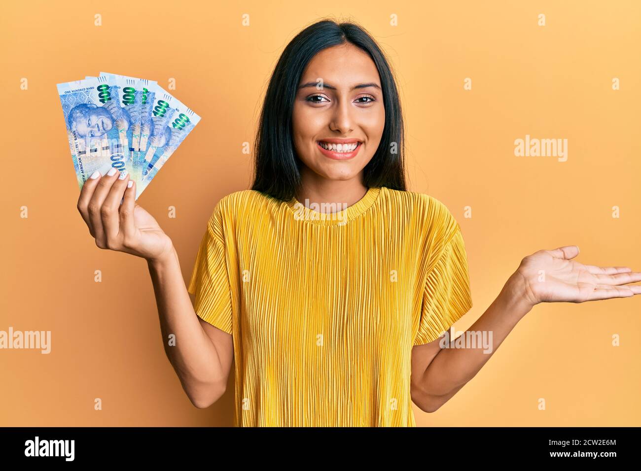 Young brunette woman holding south african 100 rand banknotes ...